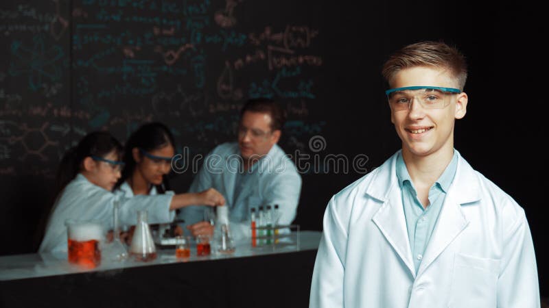 Student Looking at Camera while Diverse Group Doing Experiment ...