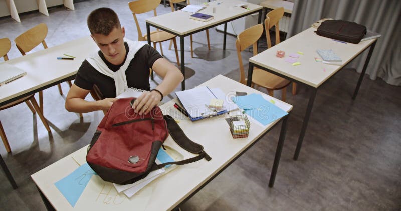 Student in Classroom after Class is Over Packing His Backpack. Getting ...