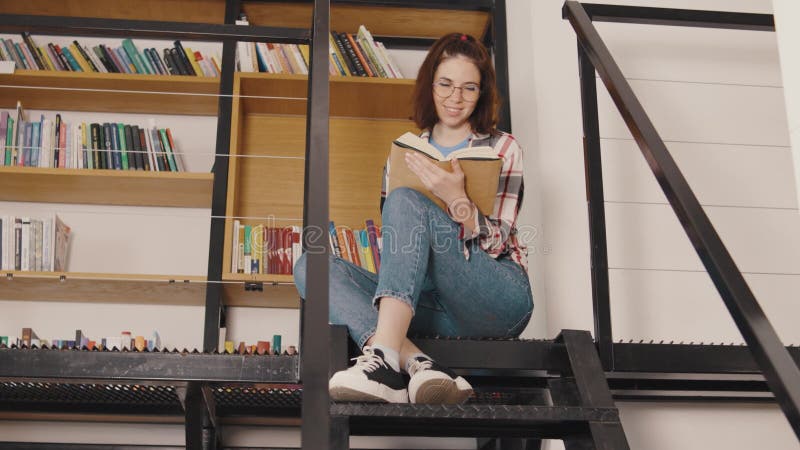 Young Woman Student Reading a Book in the Library or Classroom ...