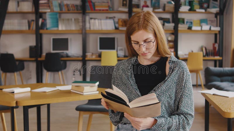 Young Woman Student Reading a Book in the Library or Classroom ...