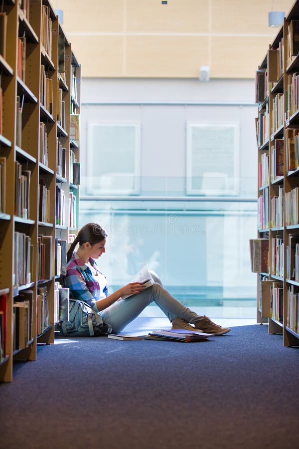 Student Reading Book while Sitting Against Bookshelf at Library Stock ...