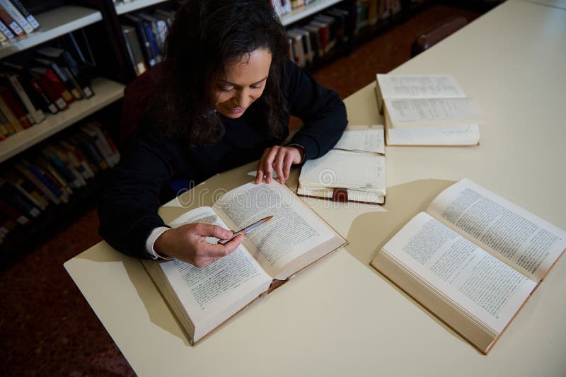 Student Reading Books in a Library Environment while Studying and ...