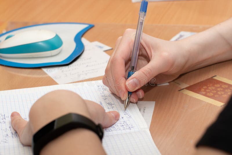 Student`s Hand Writes in a Notebook on a Desk with a Mouse and a ...