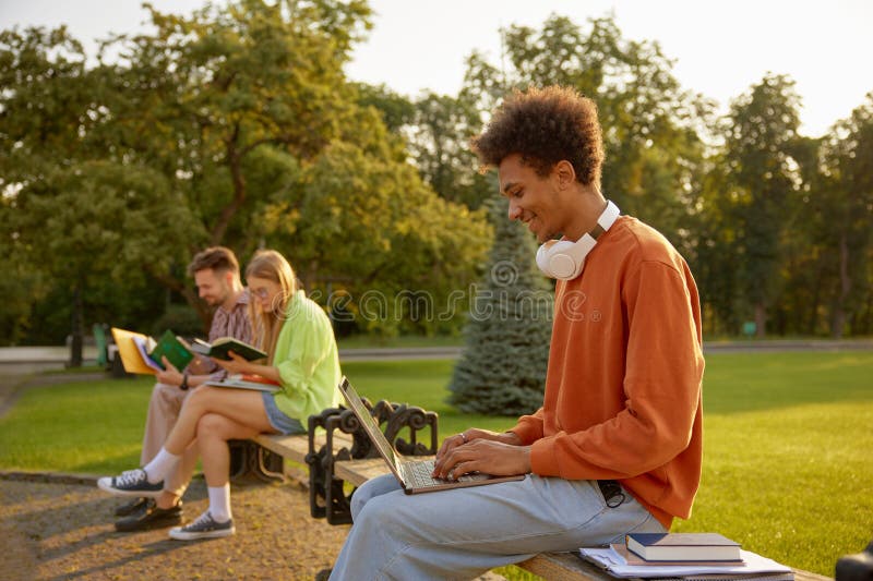 Student Sitting on Bench in University Park and Studying on Laptop ...