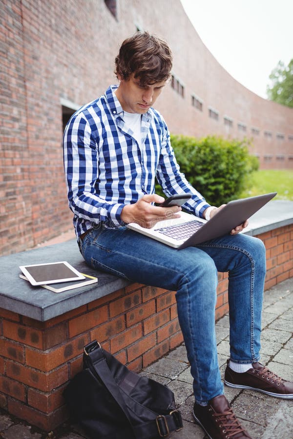 Student Sitting with Laptop Using Mobile Phone in Campus Stock Photo ...