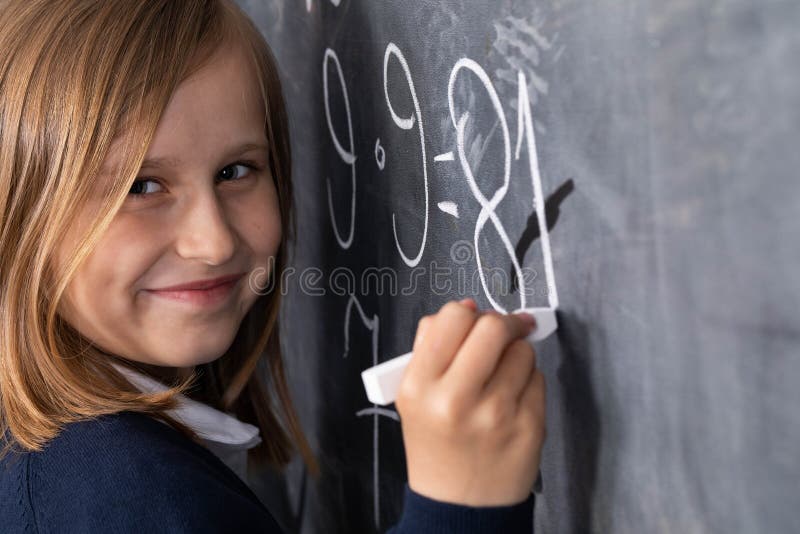 The Student Solves a Math Problem Standing at the Blackboard in Her ...
