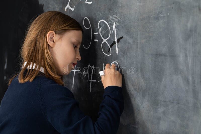 The Student Solves a Math Problem Standing at the Blackboard in Her ...