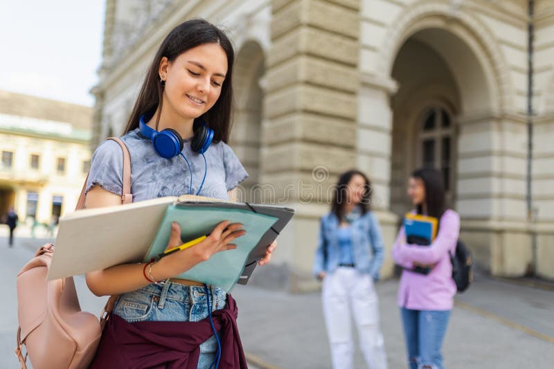 Student Standing with Her Note-book while Her Friends are Studying ...