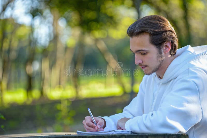 Student Studies in Nature. a Young Guy is Studying Outdoors Sitting in ...