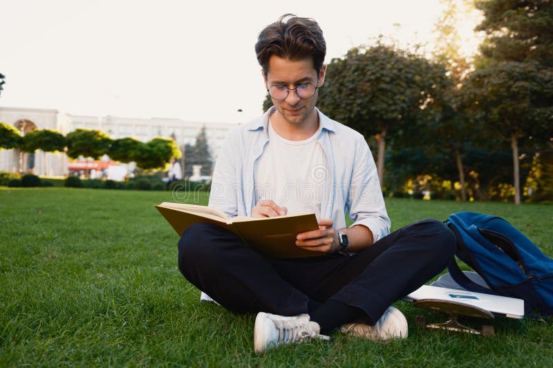 A Student Studies Outdoors while Writing in a Notebook during a Sunset ...