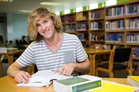 Male Student Studying Open Textbook, Writing Notes at Library Study ...