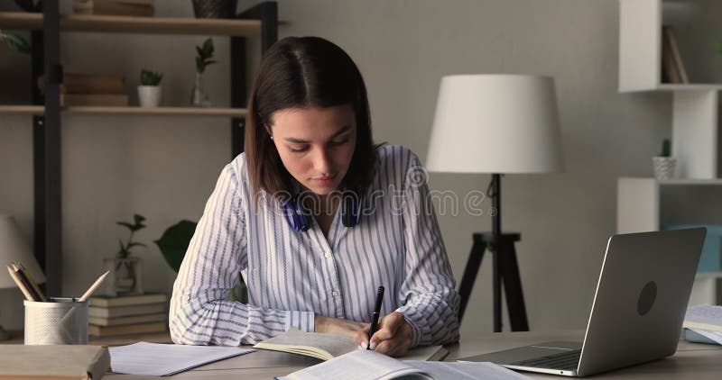 Student Studying Using Internet Resources, Writing Notes on Copybook ...