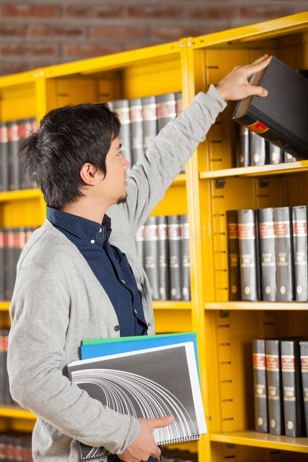University Student Taking A Book From Shelf In Library Stock Photo ...