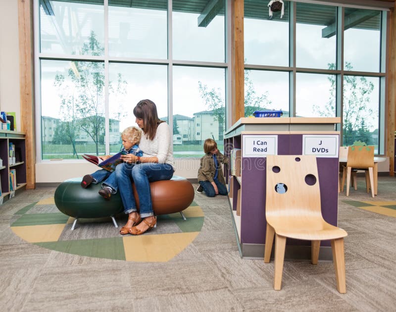 Teacher Reading Book To Children in Library Stock Photo - Image of ...