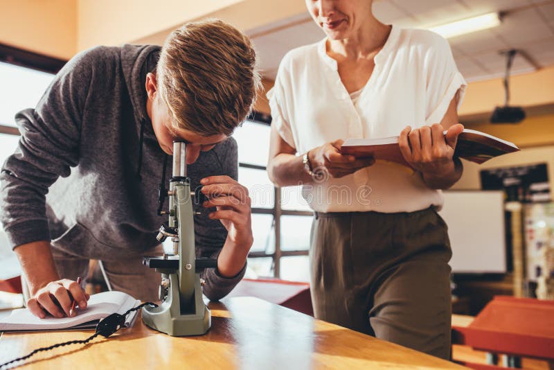 Student with Teacher in School Laboratory Looking in Microscope Stock ...
