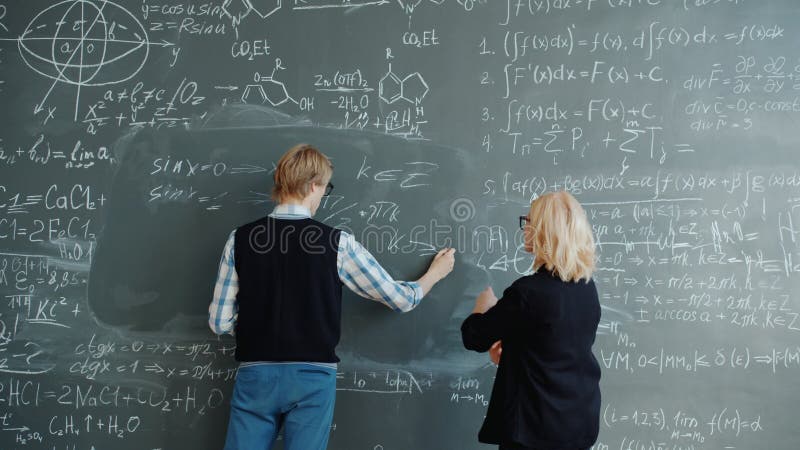 Student and Teacher Working with Chalkboard Writing Formulas in ...