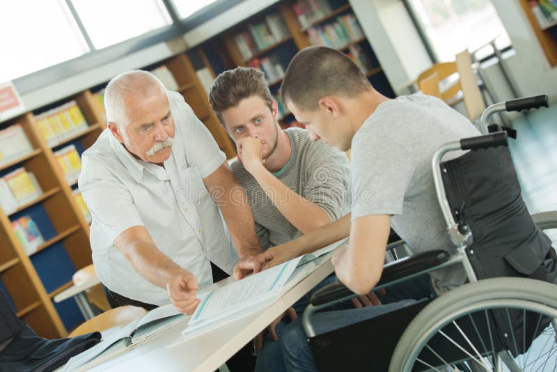 Student in Wheelchair Talking with Classmate and Teacher in Library ...