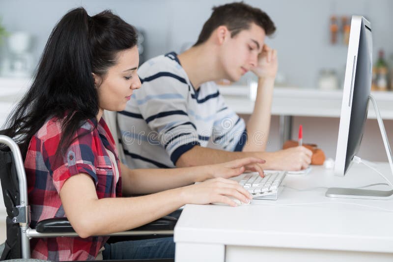 Student in Wheelchair Working with Classmate in Library Stock Photo ...