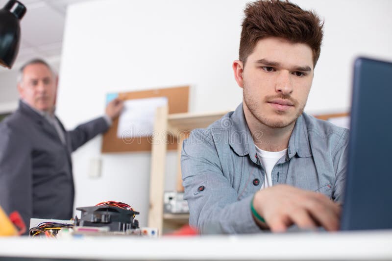 Student Working on Computer Listening To Teacher in Workshop Stock ...