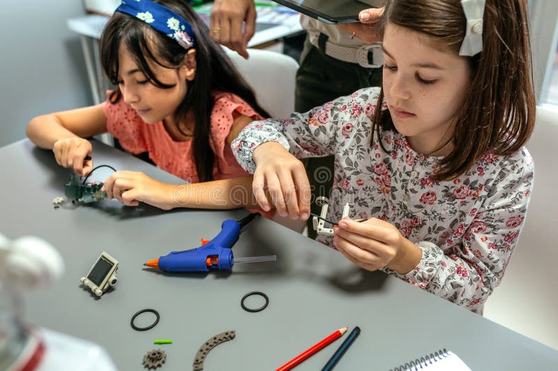 Female Teacher Helping Girl Student Assemble Electrical Circuit ...