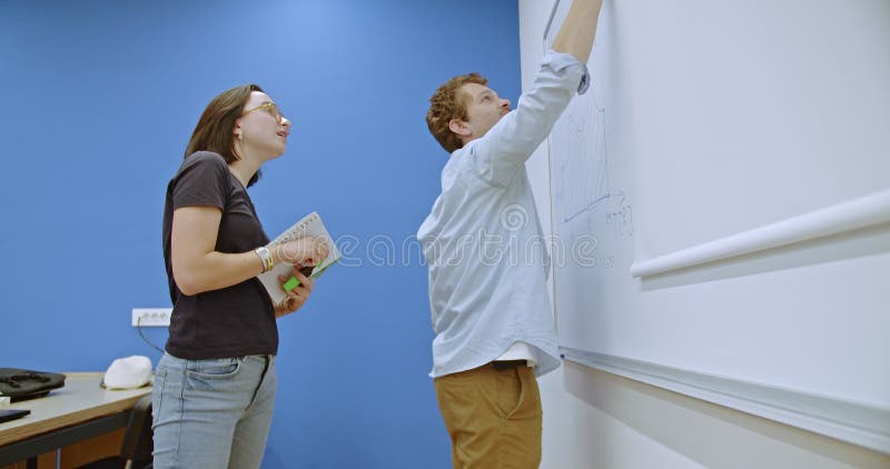 Students Collaborate at Whiteboard, Drawing Diagrams and Formulas in ...