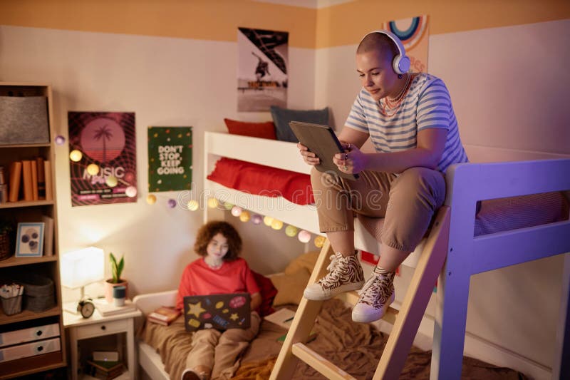 Students Dorm Room with Bunk Bed and Two Young Women Using Tech Devices ...
