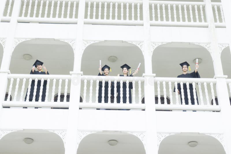 Students in Feeling Happy with Graduation Gowns Stand at Corridor ...