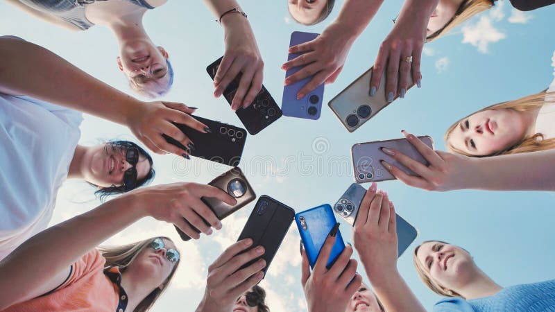 Students Forming a Circle and Sharing Content on Smartphones Against a ...