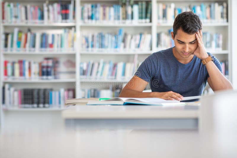 Students in a Library - Handsome Student Reading a Book Stock Image ...