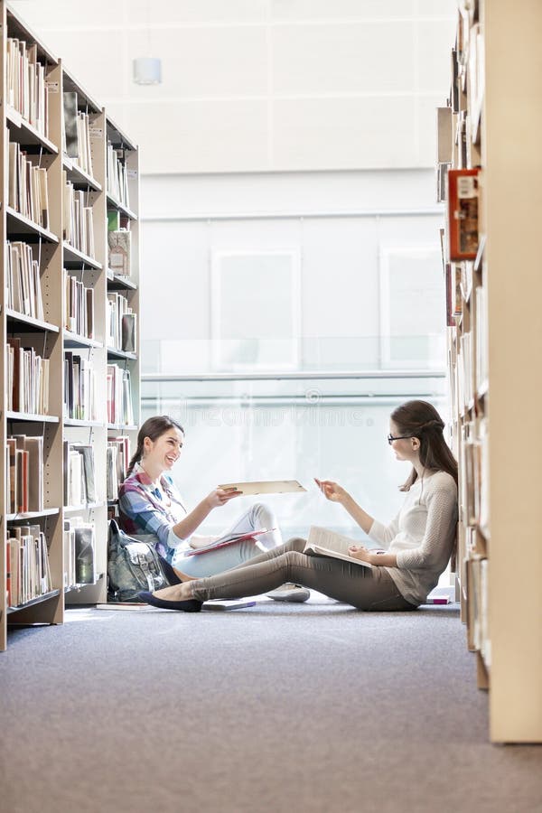 Students Passing Book while Sitting at University Library Stock Image ...