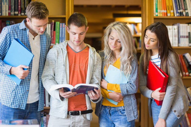 Students Reading Book Against Bookshelf in Library Stock Photo - Image ...
