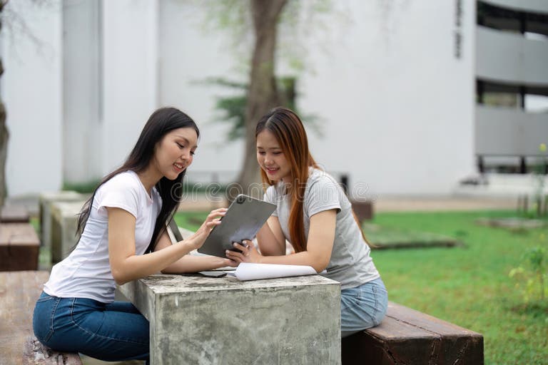 Students Reviewing Study Materials Together Outdoors, Engaging with a ...