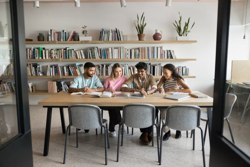 Students Sitting at Table in Library Preparing University Assignment ...