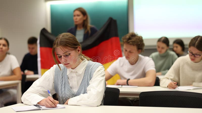 Students Sit in Classroom, Teacher Stands Behind with Flag of Germany ...
