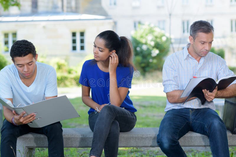 Students and Teacher Sat Looking at Files on Bench Outdoors Stock Photo ...