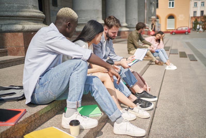 Students with Textbooks Sitting on the Steps. Stock Image - Image of ...
