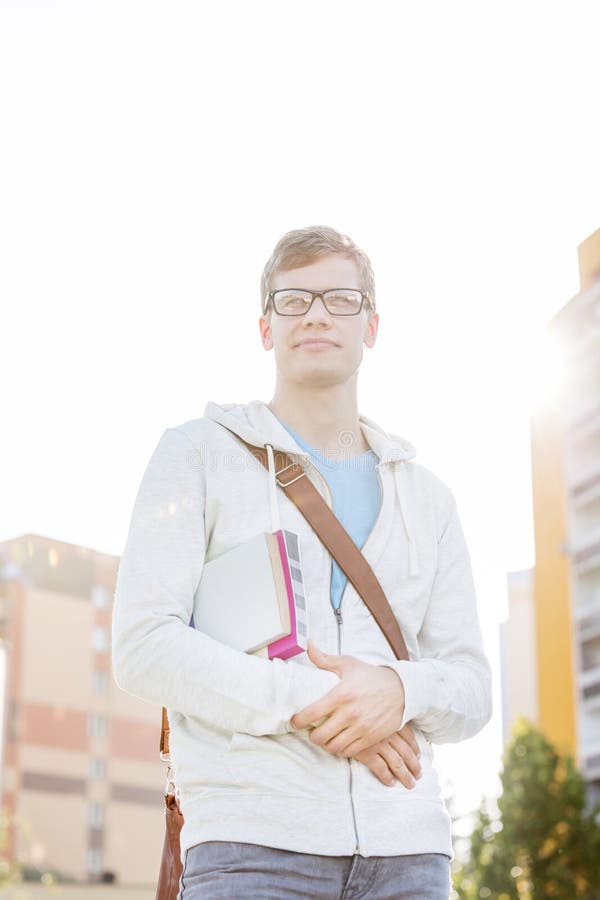 Portrait of Handsome Student with Books in University Campus Against ...