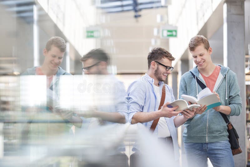 Friends Reading Books while Discussing at Library in University Stock ...