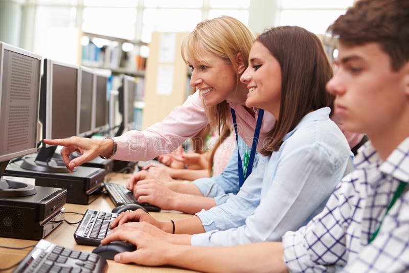 Students Working at Computers in Library with Teacher Stock Image ...