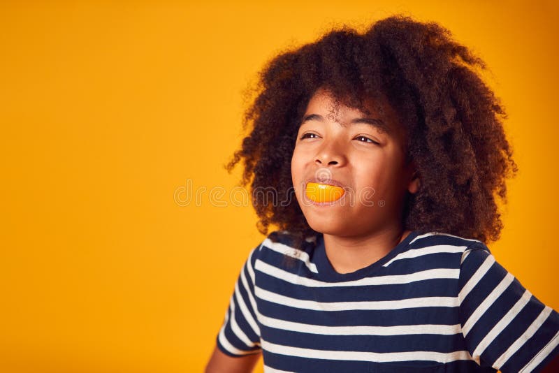 Studio Portrait of Smiling Boy Pulling Funny Face with Orange for Mouth ...