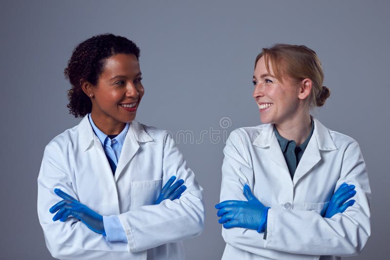 Studio Portrait of Two Smiling Female Doctors or Lab Workers in White ...