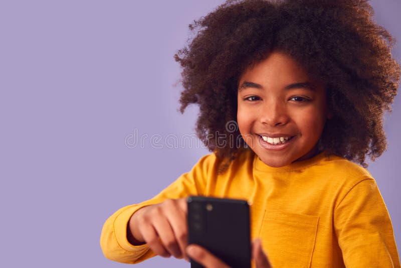 Studio Portrait of Young Boy Using Mobile Phone Against Purple ...
