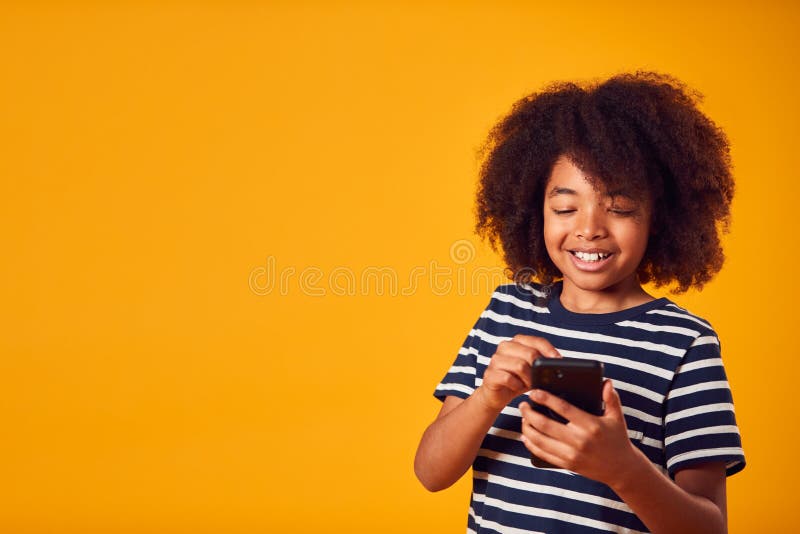 Studio Portrait of Young Boy Using Mobile Phone Against Yellow ...