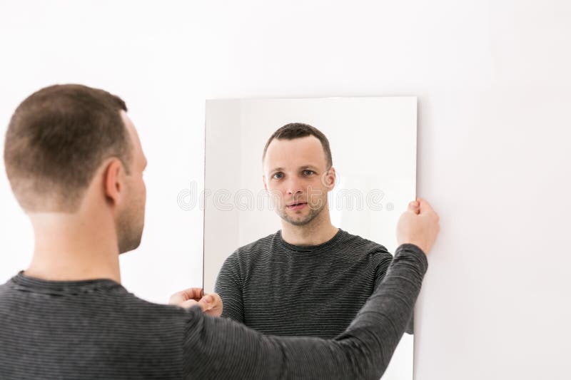 A Man Standing in Front of a White Wall with a Mirror Stock Image ...