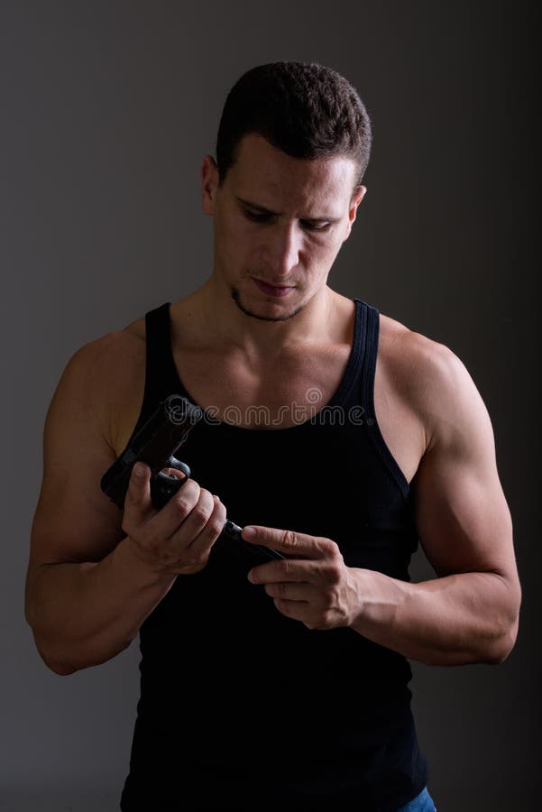 Studio Shot Of Young Muscular Persian Man Reloading Gun In Dark Stock ...