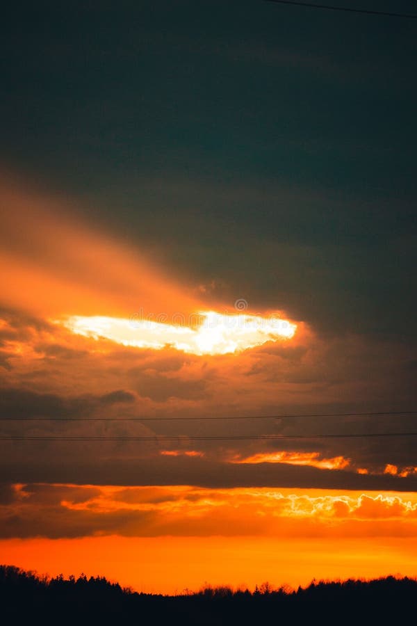 Stunning Landscape Featuring an Orange Sunset Behind the Clouds Over the Silhouette of a Forest ...