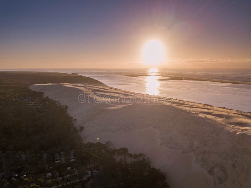 The Sun Rises Over a Beach with Water and Sand on it Stock Photo ...