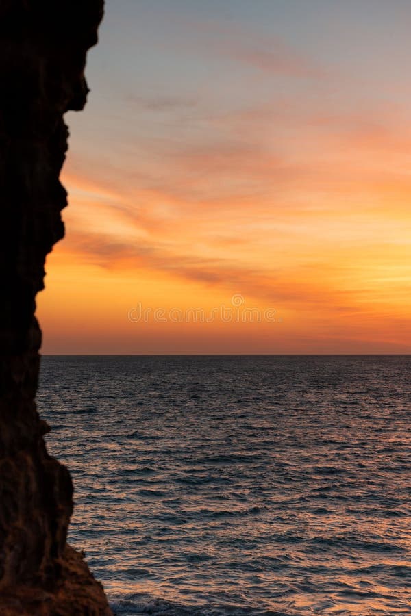 The Sun Sets Over the Ocean from Behind Some Rocks and Some Cliffs ...