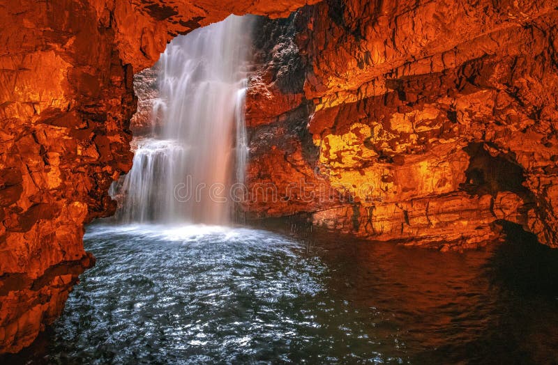 Stunning View of a Waterfall Inside a Cave Illuminated by Warm Lights ...