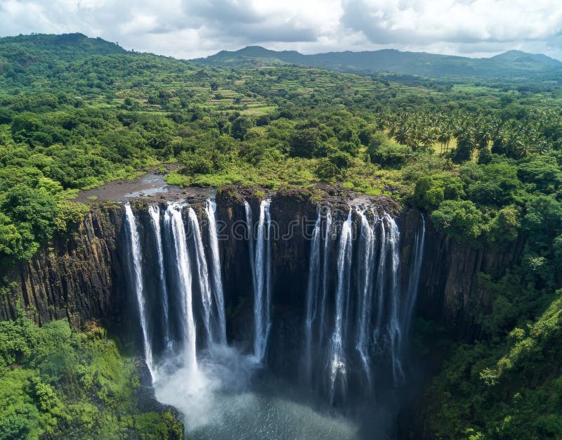 A Stunning Waterfall Tumbles Down a Rich Green Cliffside into a River ...